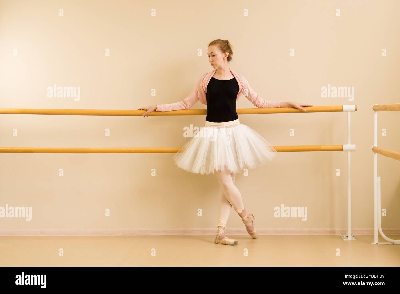 Ballet dancer standing in relaxed pose at barre during practice Stock ...