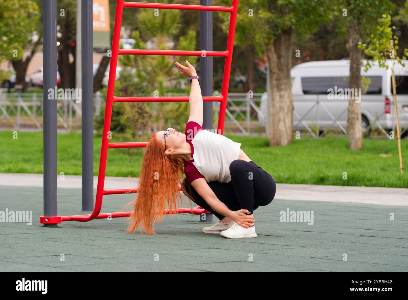 Woman stretching upward while squatting during outdoor exercise in a ...