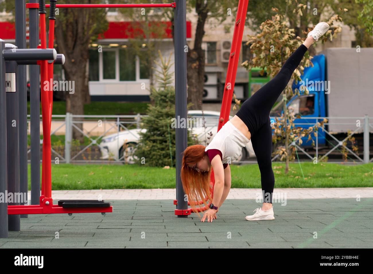 Woman performing a leg lift stretch while bending forward, using ...