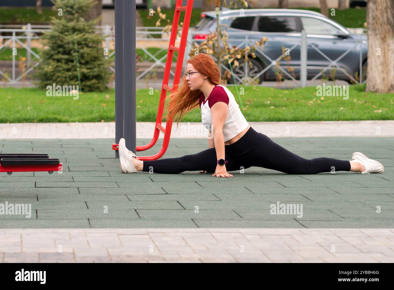 Woman performing the splits as part of her outdoor stretching routine ...
