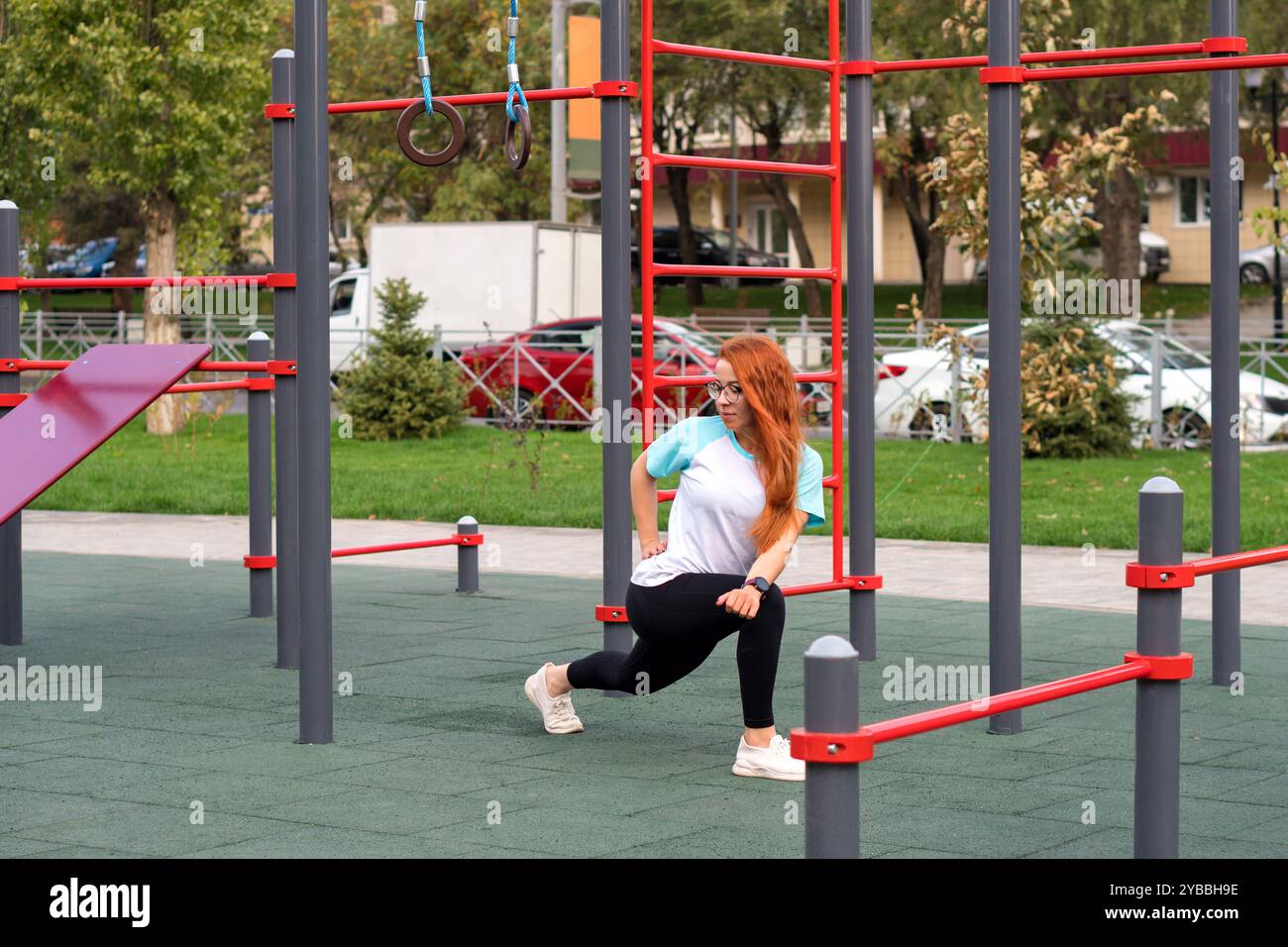 Woman performing lunges during outdoor exercise at playground, showing focus and dedication ...