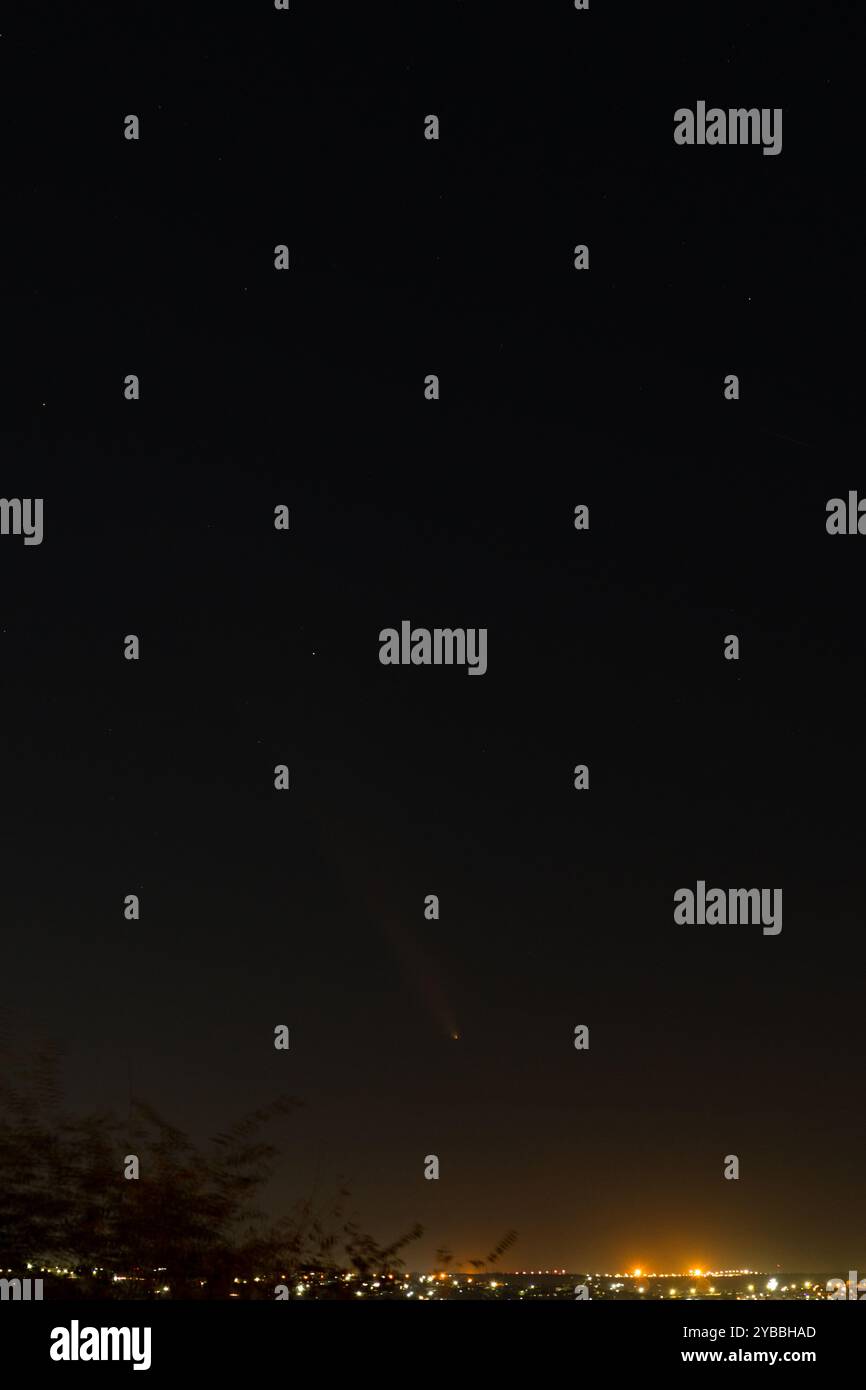 Comet Tsuchinshan Atlas 2023 A3, its glowing tail faintly visible, travels through the night sky ...