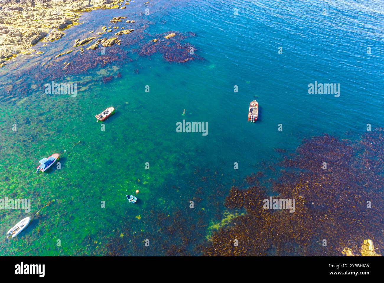 small fishing boats anchored in a small natural harbor on a rocky ...