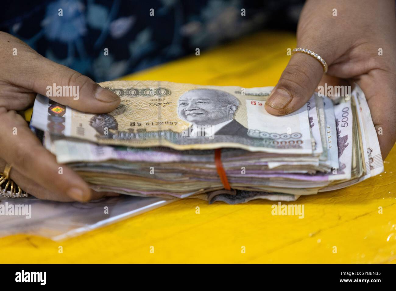 A vendor holding a stack of Cambodia notes (riel/ KHR) at Central ...