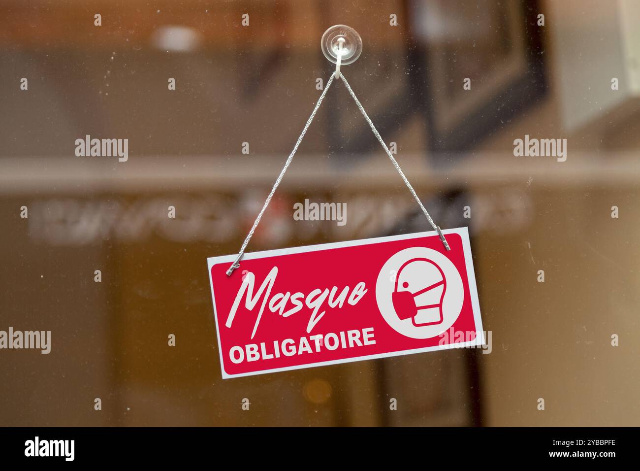 Red sign hanging at the glass door of a shop with written in French ...