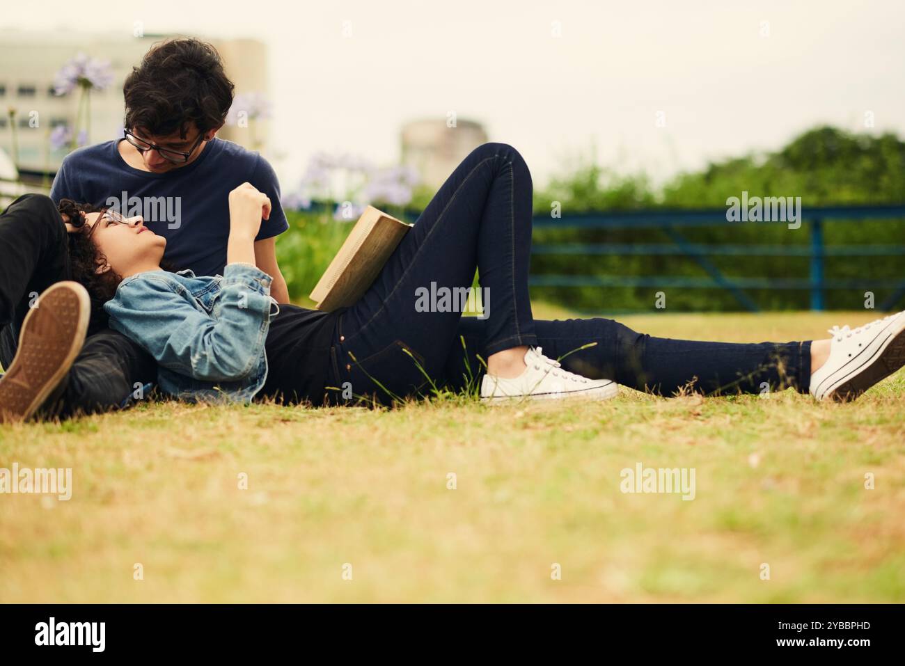 Couple, teenager and love in park for reading, bonding and relax ...