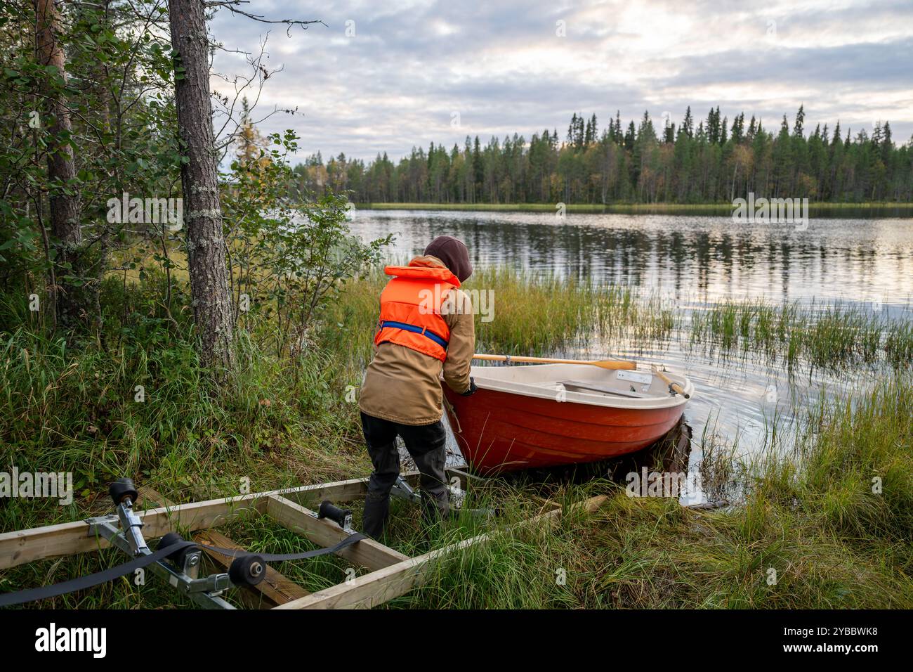 man pulling a boat into a small wooden garage on coast of lake Stock ...