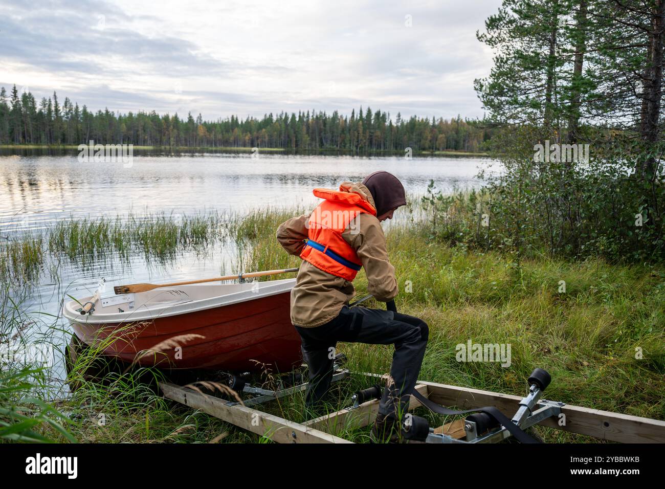 man pulling a boat into a small wooden garage on coast of lake Stock ...