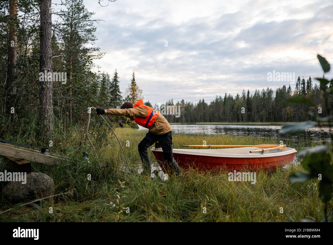 man pulling a boat into a small wooden garage on coast of lake Stock ...