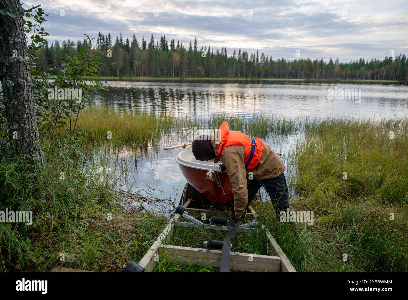 man pulling a boat into a small wooden garage on coast of lake Stock ...