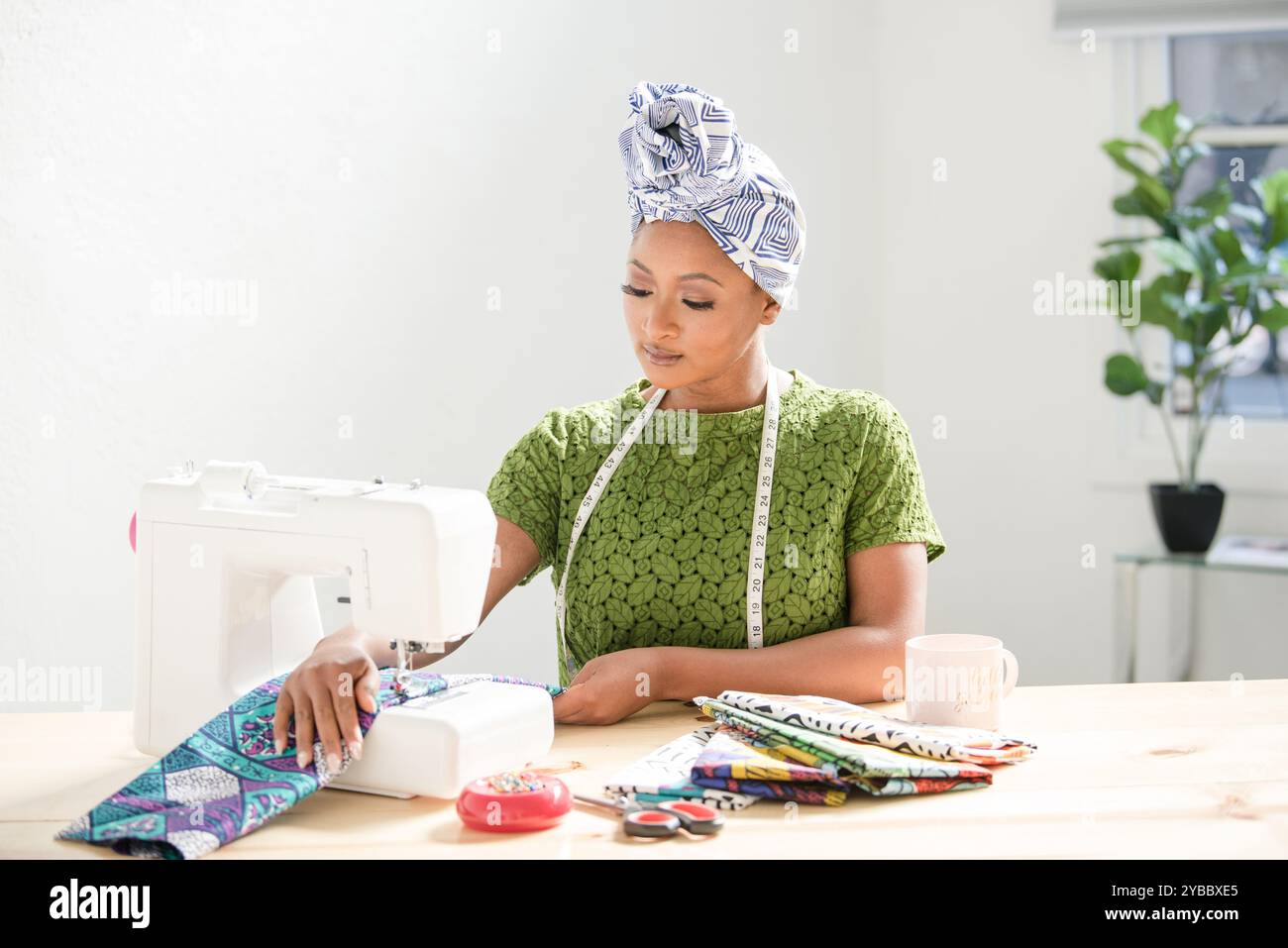 Woman using sowing machine on fabric Stock Photo - Alamy