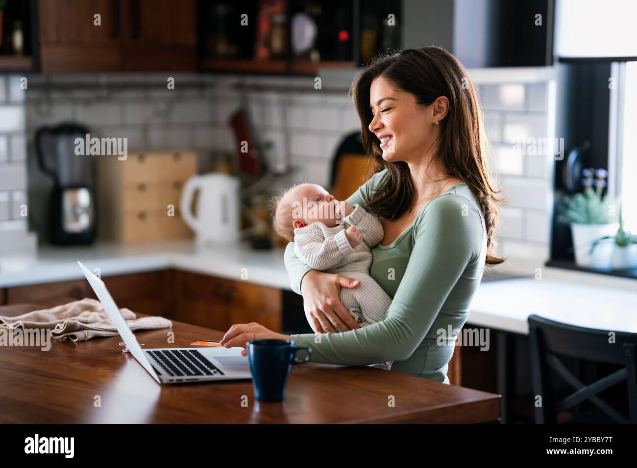 Stay at home mom working remotely on laptop while taking care of her ...