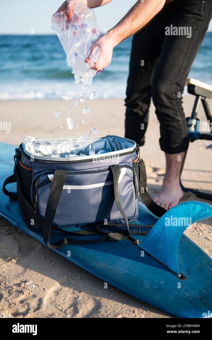 Solo man pouring ice in portable cooler bag at beach hangout Stock ...