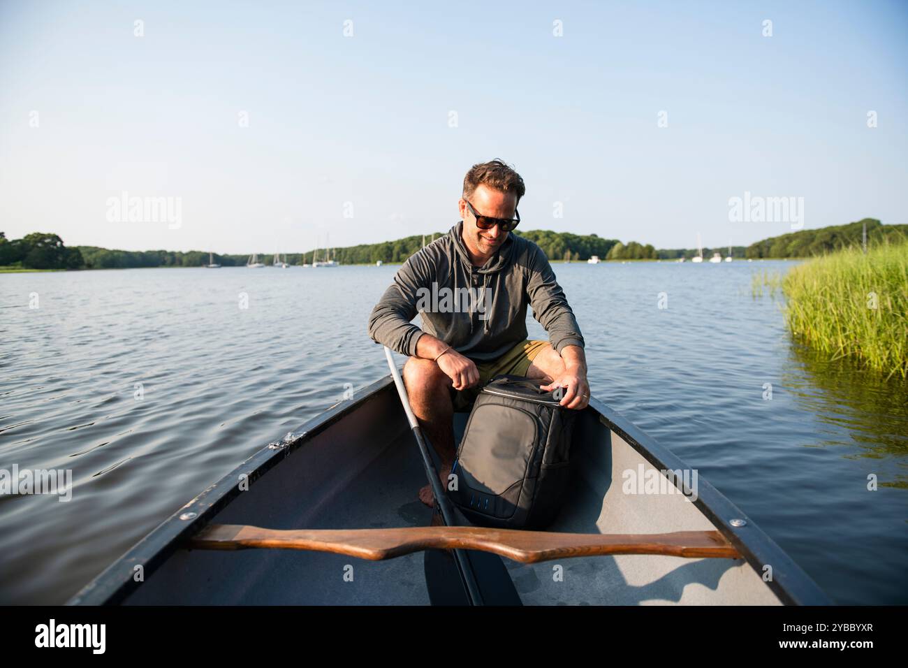 Man loading backpack in canoe on summer day Stock Photo - Alamy