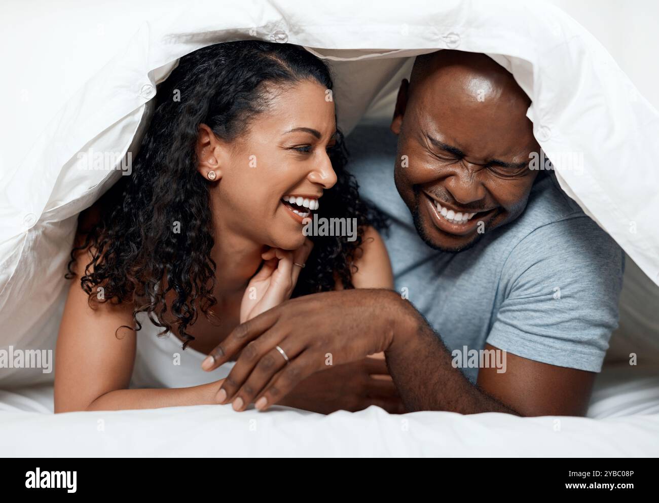 Couple, blanket cover and laughing in bedroom, love and funny joke for ...
