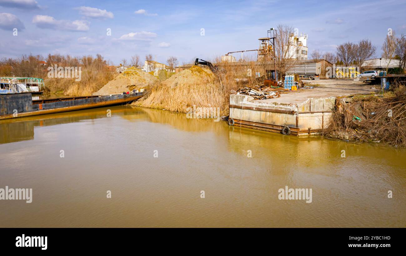 Pier, dock of concrete at river coast with piled trash of old large ...
