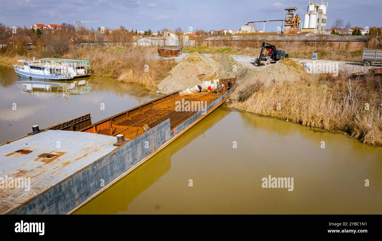 Above top view on workers as they cutting old large vessel, barge ...