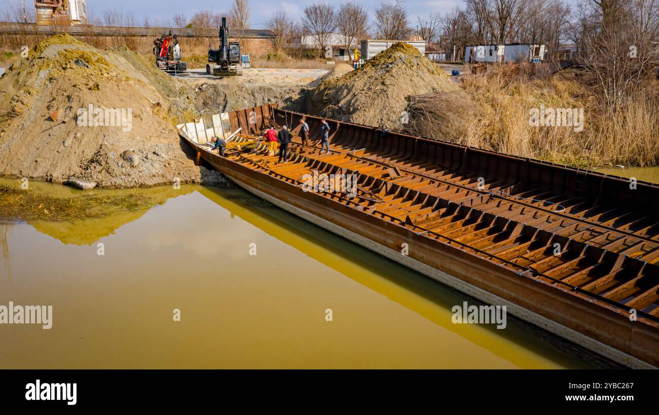 Above top view on workers as they cutting old large vessel, barge ...
