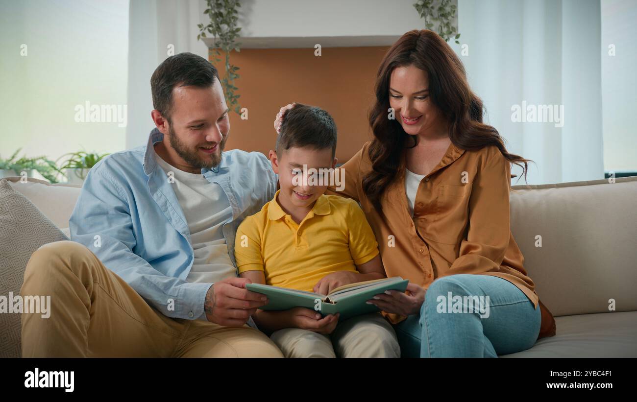 Happy caucasian family dad mom son reading fairytale story book on sofa in cozy living room ...