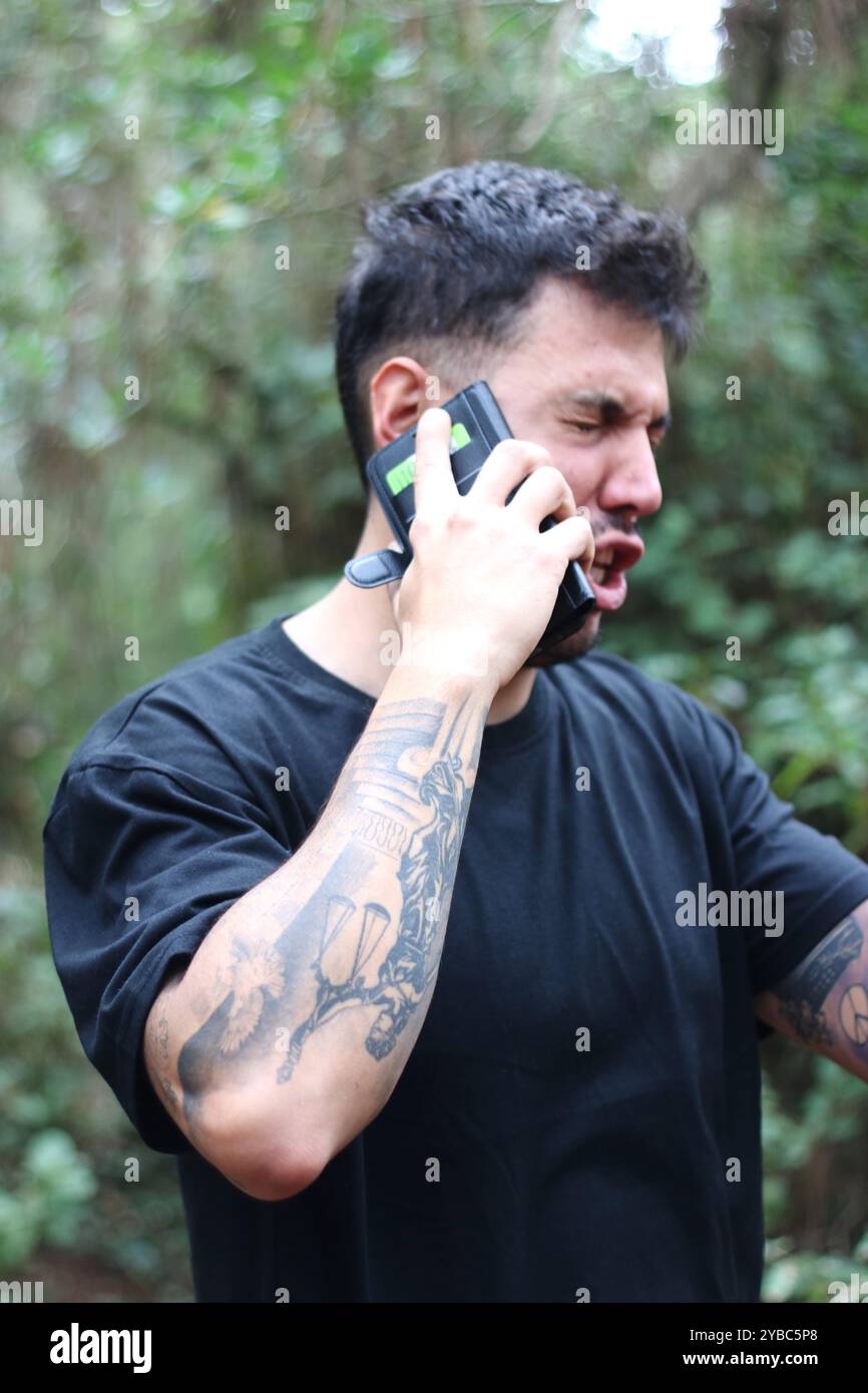 A frustrated young man yells into his cell phone during an intense ...