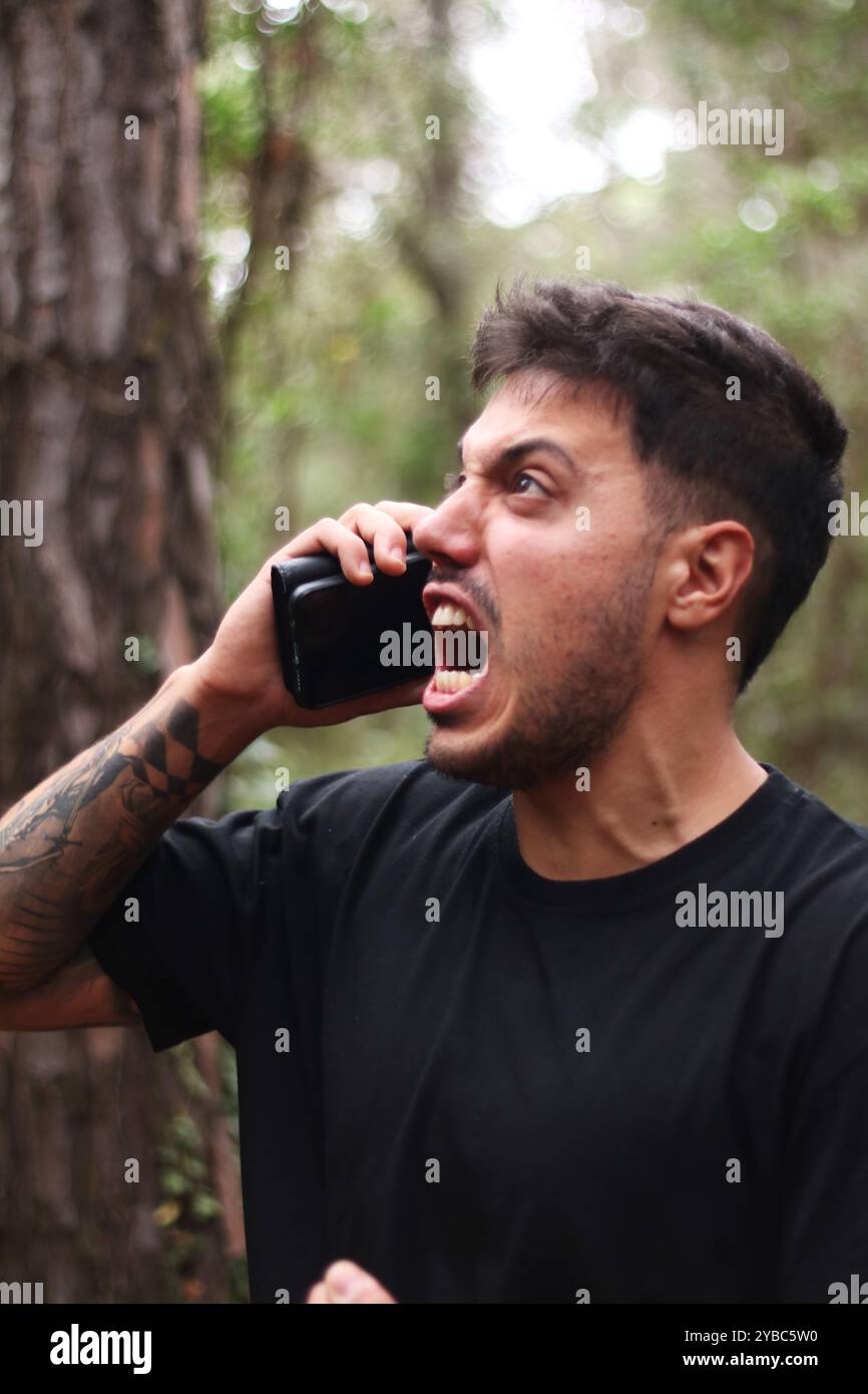 A frustrated young man yells into his cell phone during an intense ...