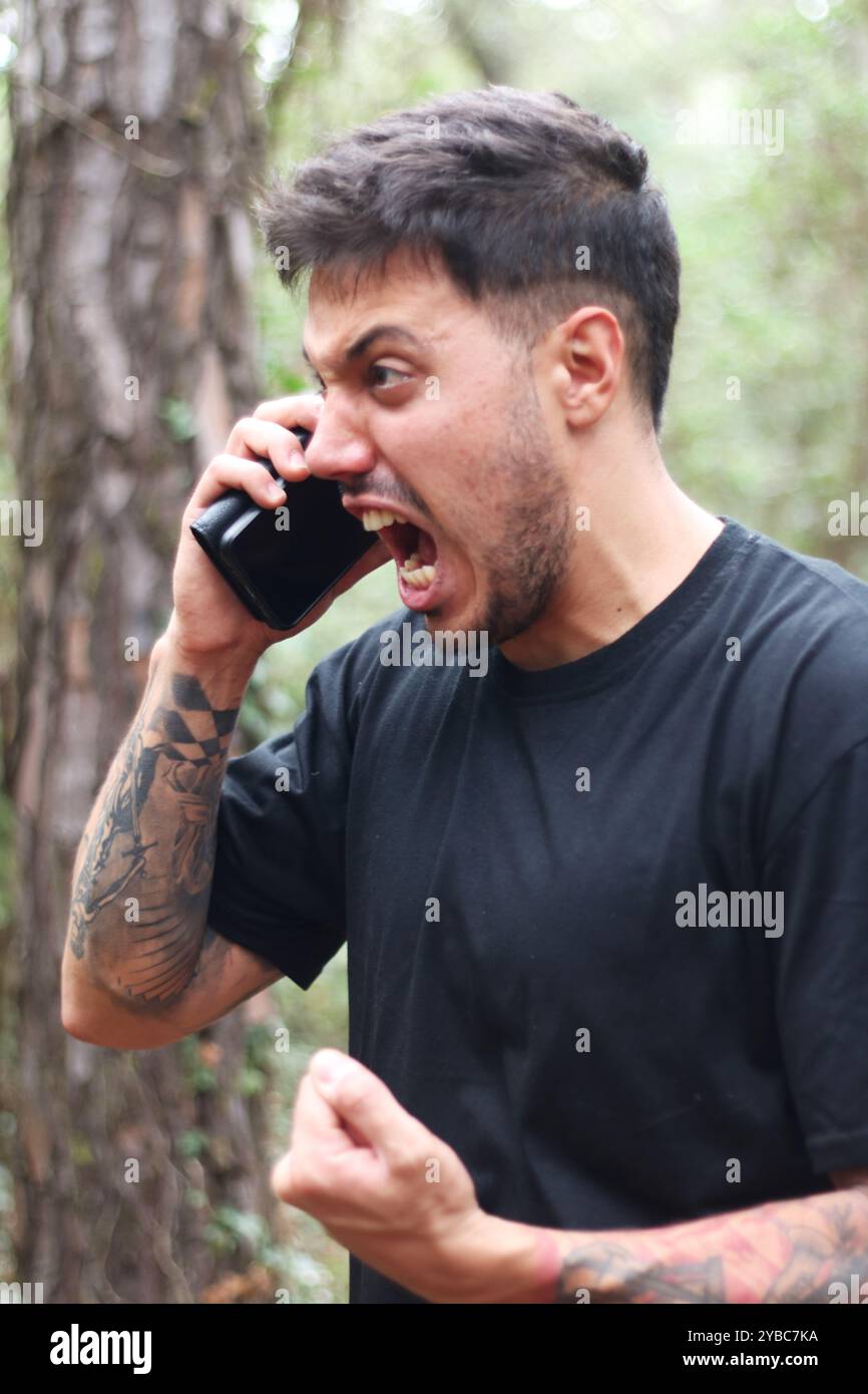 A frustrated young man yells into his cell phone during an intense ...