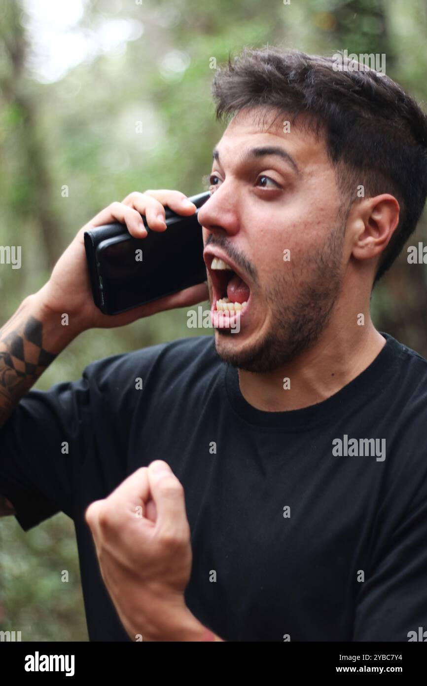 A frustrated young man yells into his cell phone during an intense ...