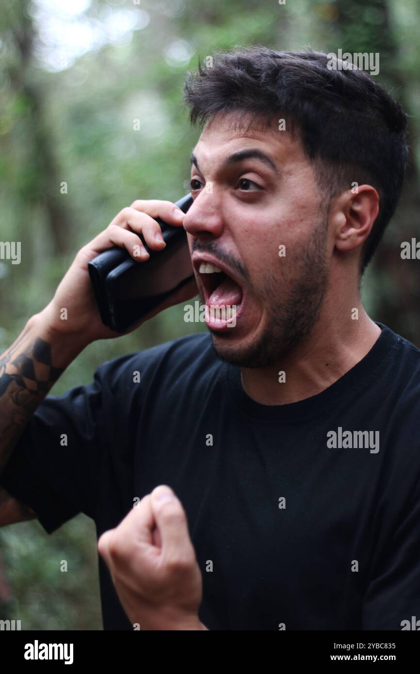 A frustrated young man yells into his cell phone during an intense ...