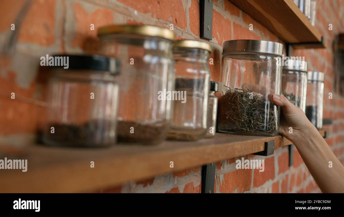 Unrecognizable woman waitress wipe dust on shelf with spices using ...