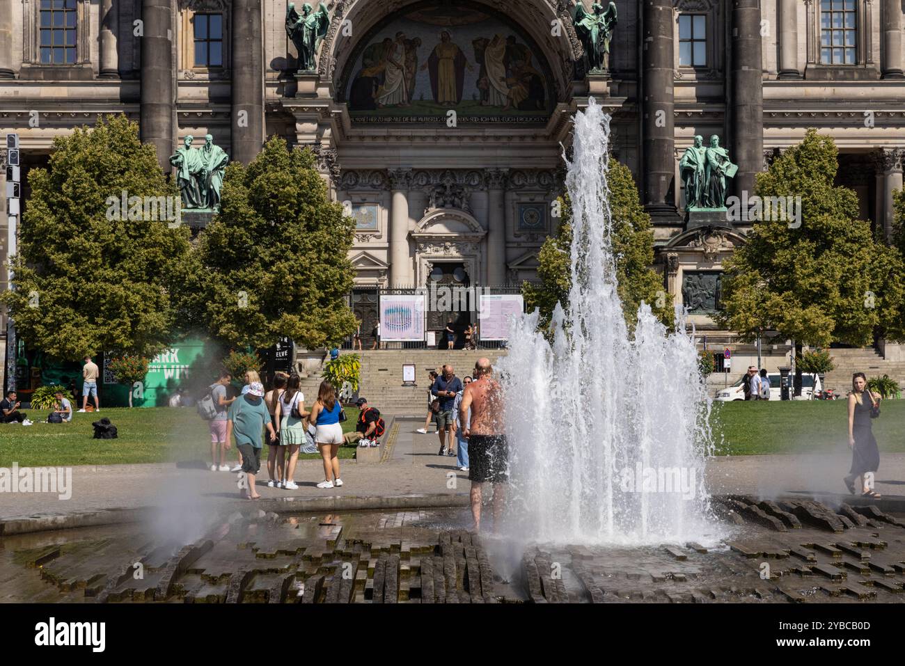 People cooling down at the Lustgarten park fountain in hot weather ...