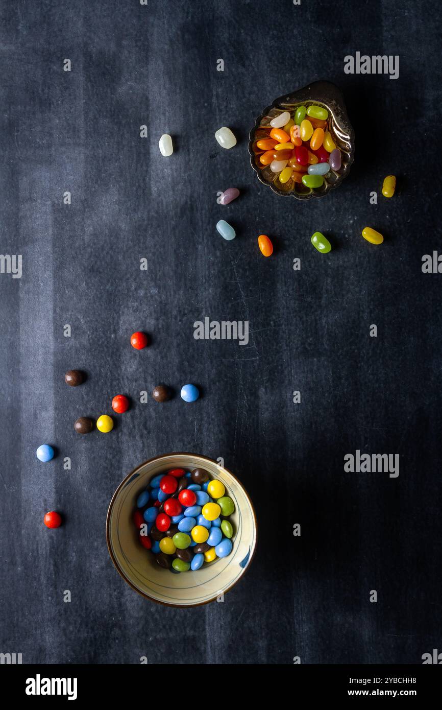 Two bowls of colorful sweet candies on black chalkboard background ...