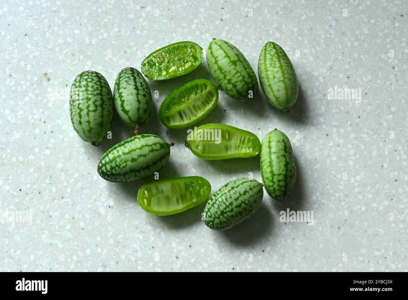 Whole and cut open small green striped fruits of Cucamelon, Melothria ...