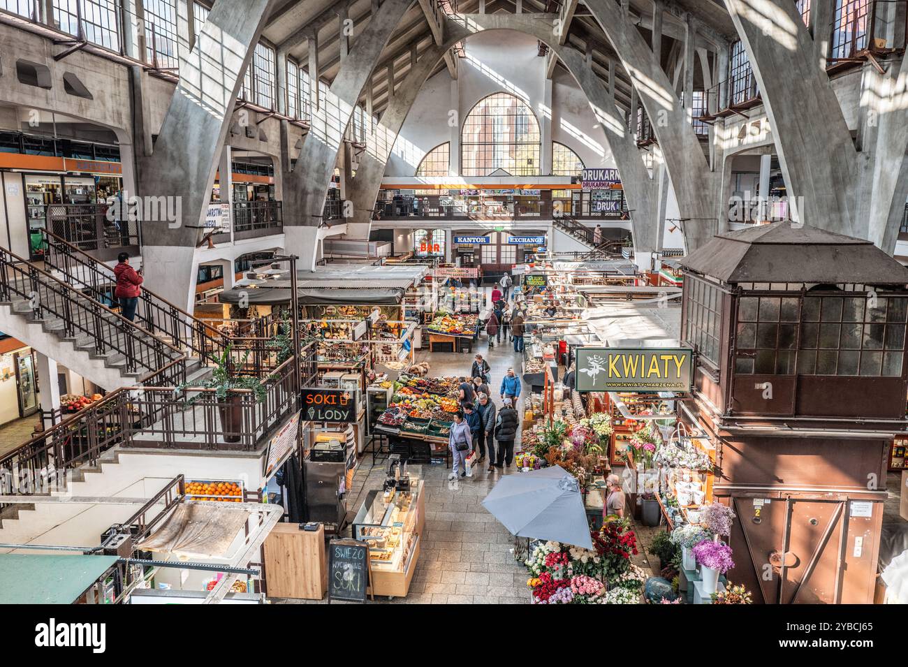 A bustling indoor market with high ceilings, showcasing vibrant stalls ...