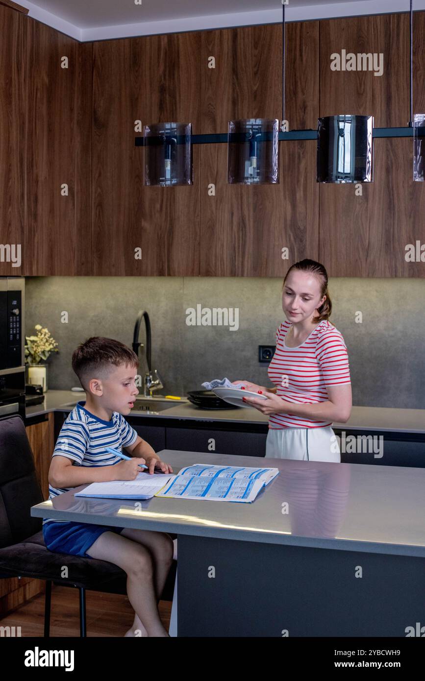 Mother helping son with homework in kitchen at home Stock Photo - Alamy