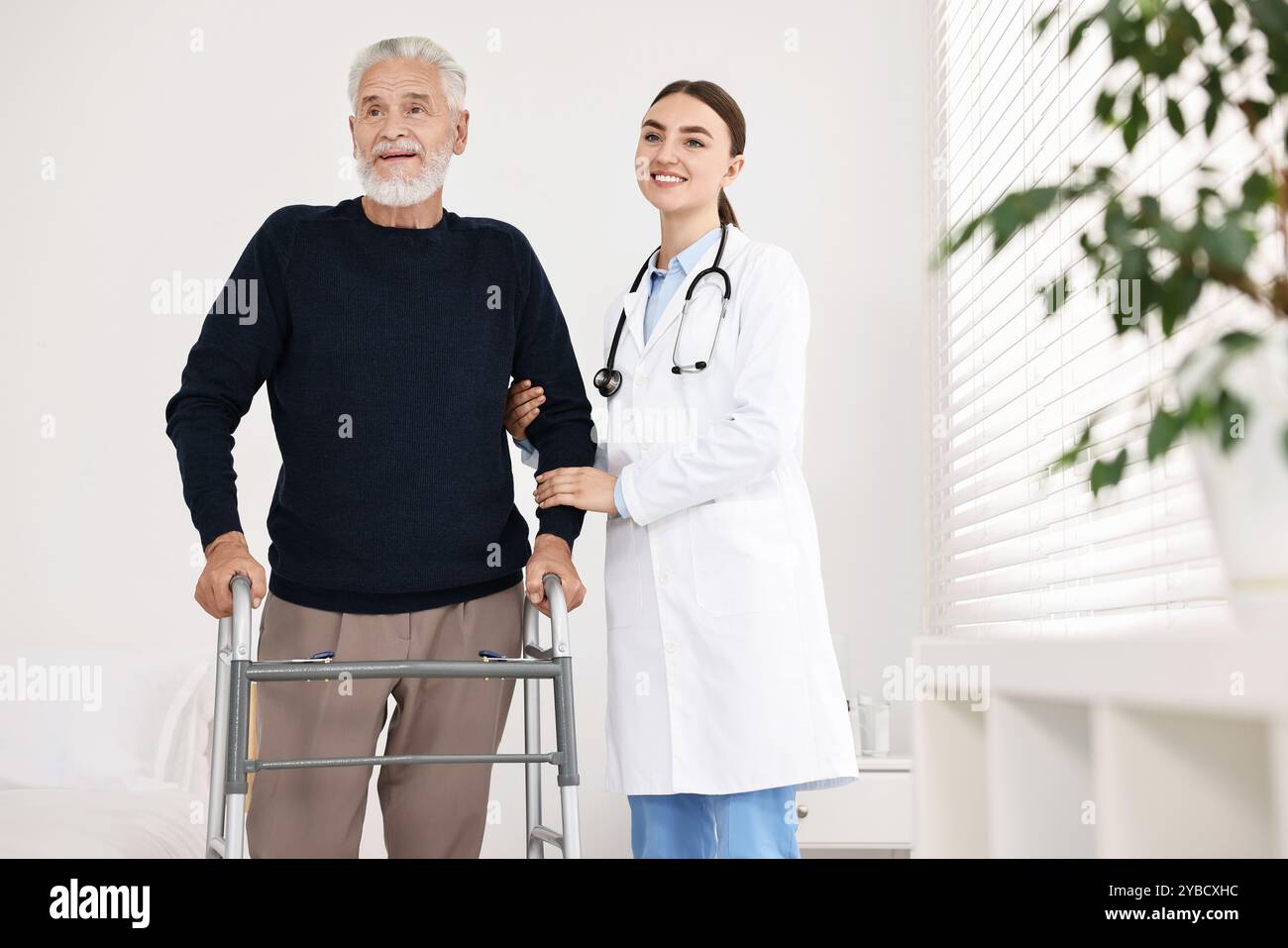 Doctor helping senior man with walking frame in clinic Stock Photo - Alamy