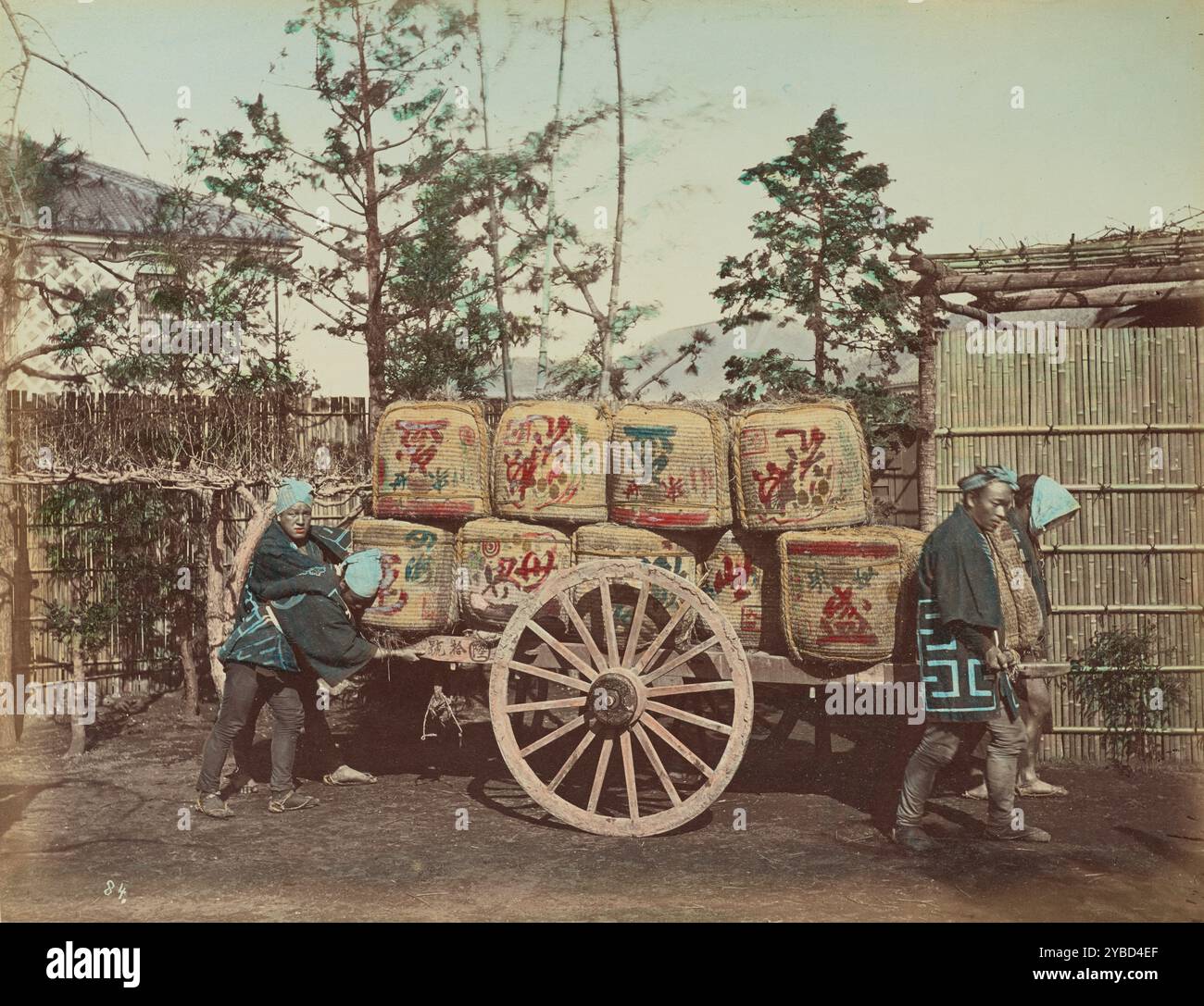 Freight cart, 1870s-1890s. Two men pulling and two men pushing a cart filled with large bales of ...