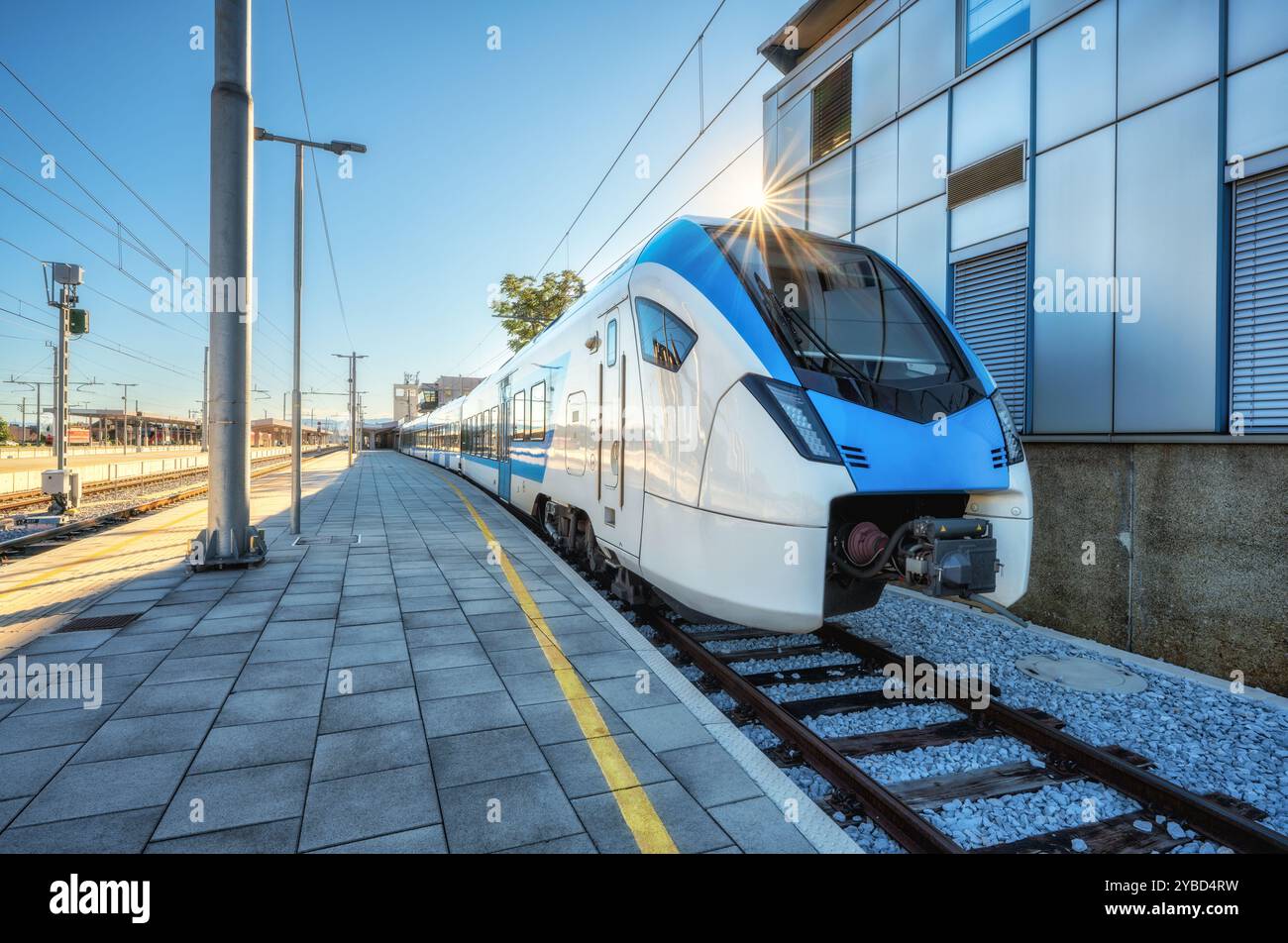 High-speed blue passenger train at railway station at sunset Stock ...