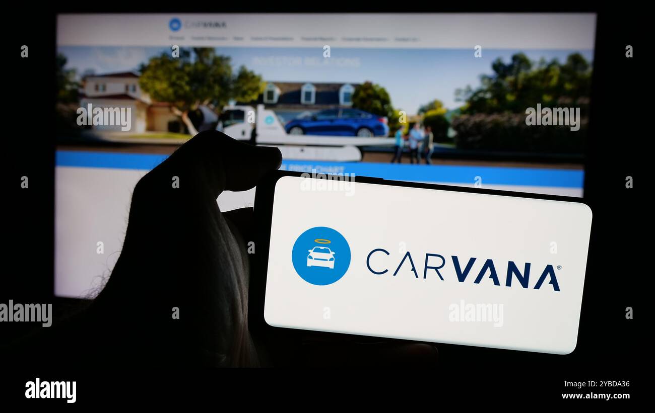 Person holding mobile phone with logo of American used car retailing company Carvana Co. on ...