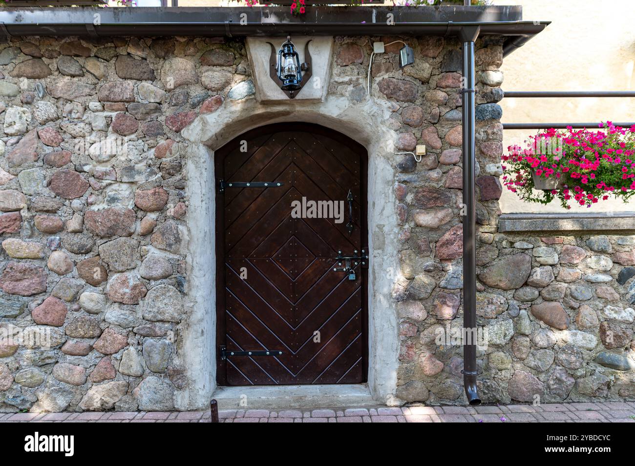 A rustic wooden door with diagonal patterns, heavy locks, and a lantern ...