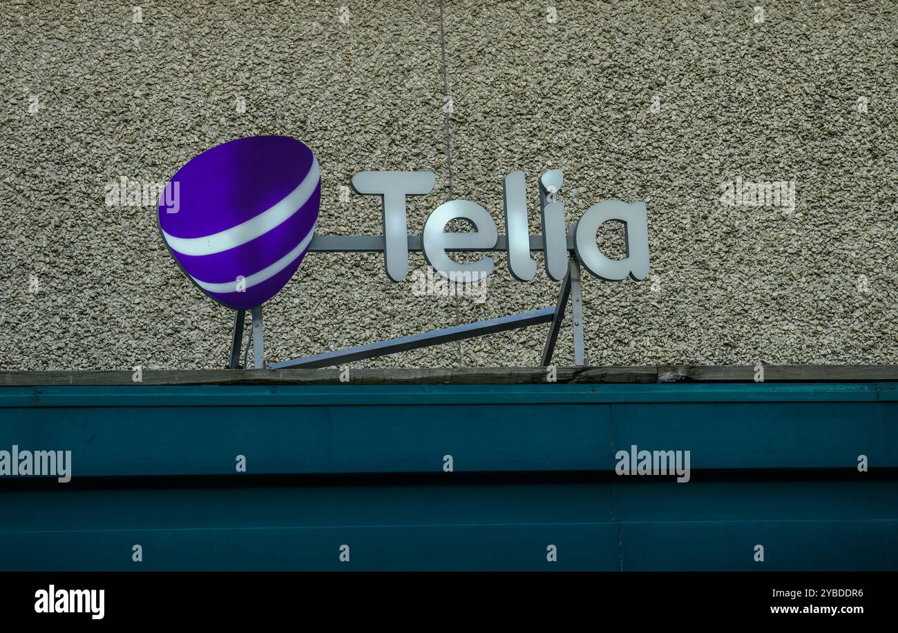 The Telia logo, featuring a purple spherical design, is mounted on a textured wall, showcasing a ...