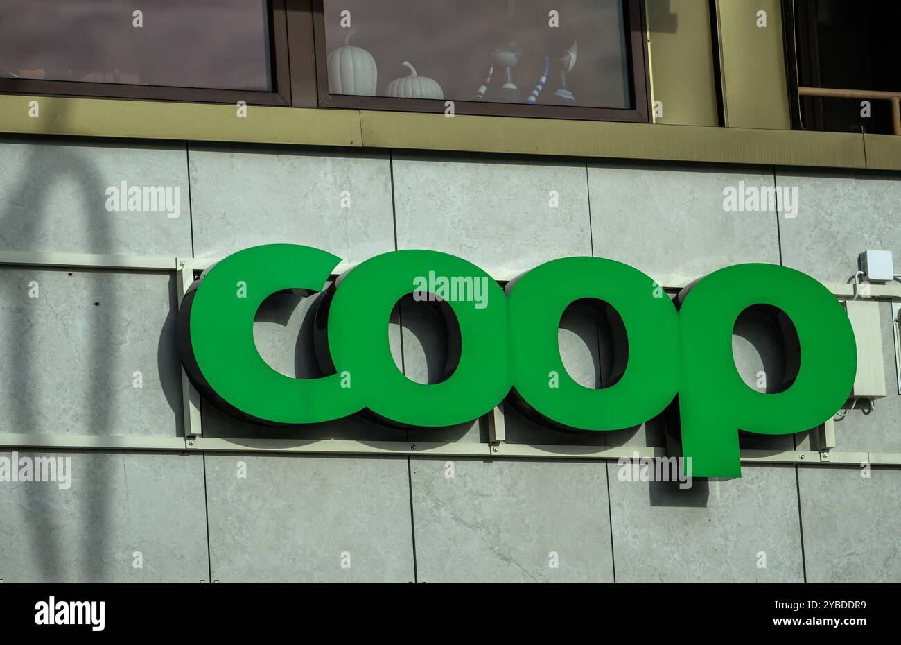 A striking green sign reading coop is mounted on a contemporary ...