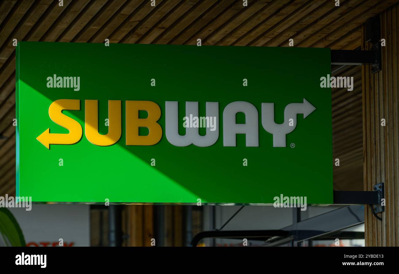 A vibrant green sign prominently features the Subway logo in a modern ...