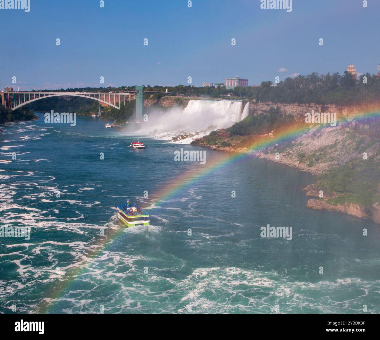 Tourists enjoy a boat ride while admiring the rainbow over the falls ...