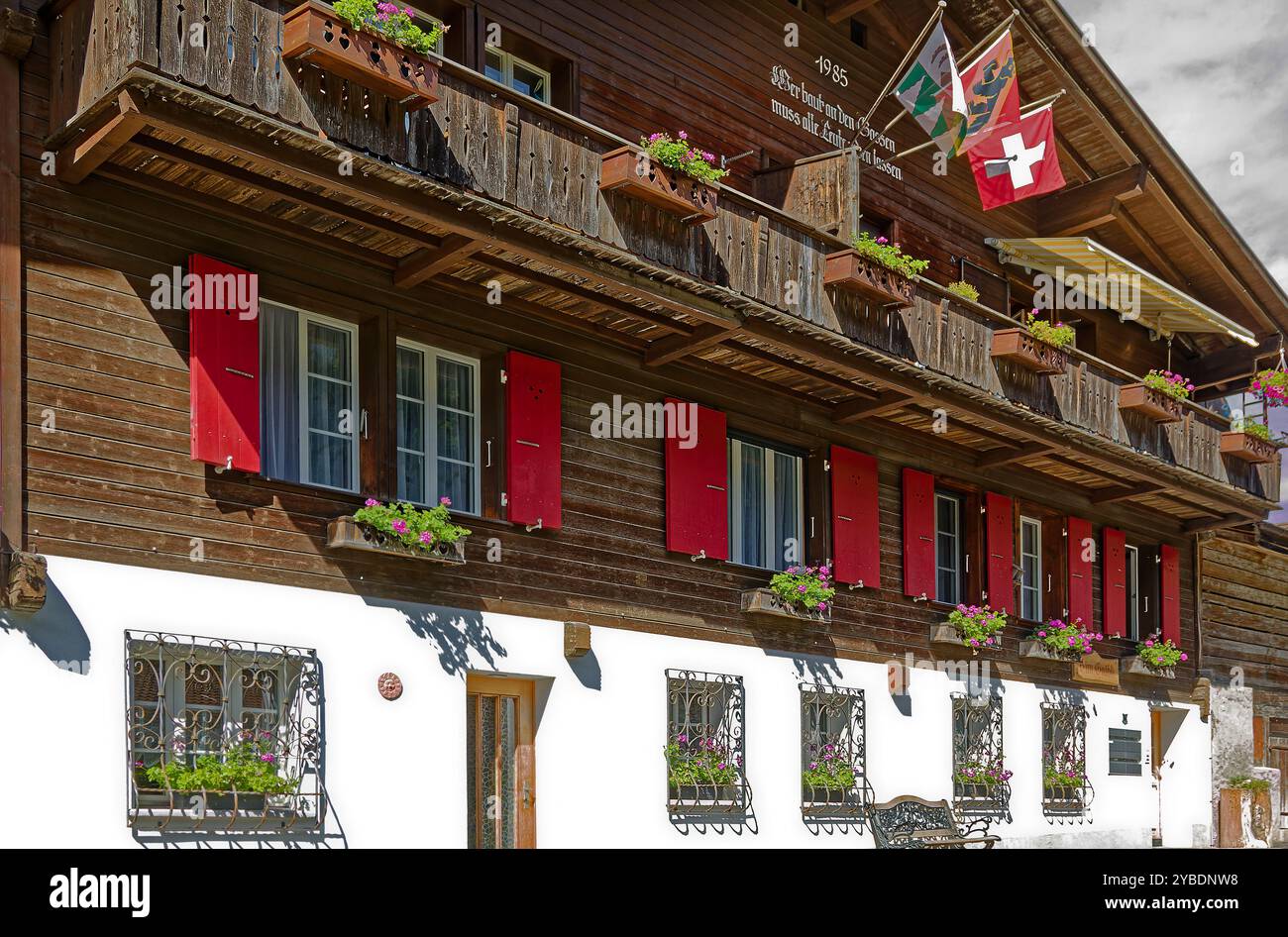 Swiss style building, wood balcony, red shutters, flowers, flags ...