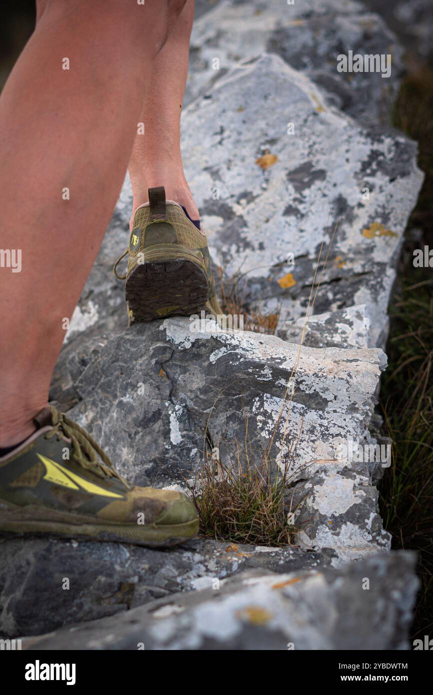 A woman taking a step on a rocky ridge in Finale Ligure, Italy Stock ...