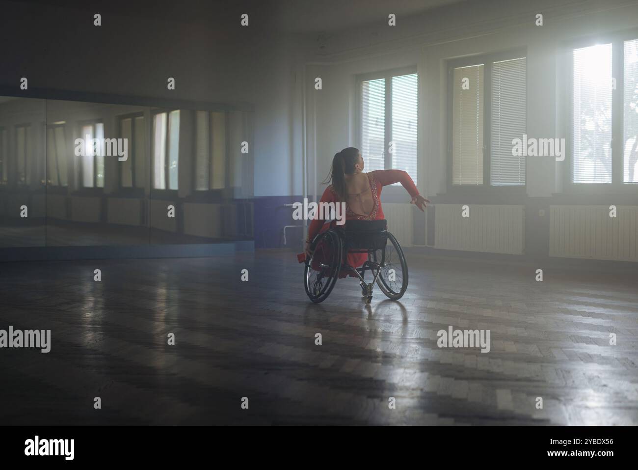 Woman in an elegant red dress dancing in a wheelchair, making graceful ...