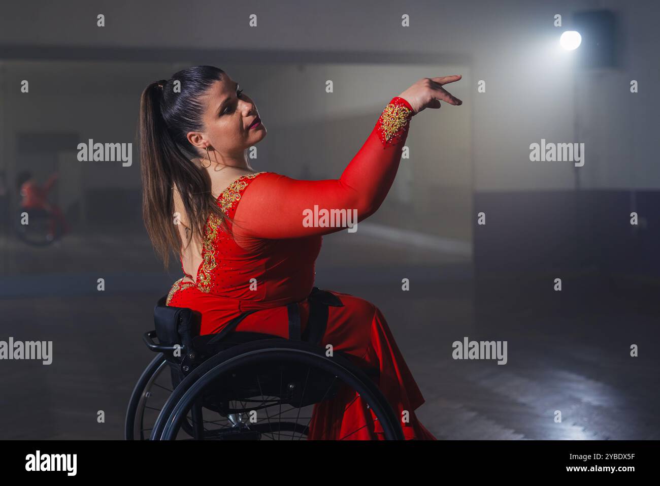 Woman in an elegant red dress dancing in a wheelchair, making graceful ...