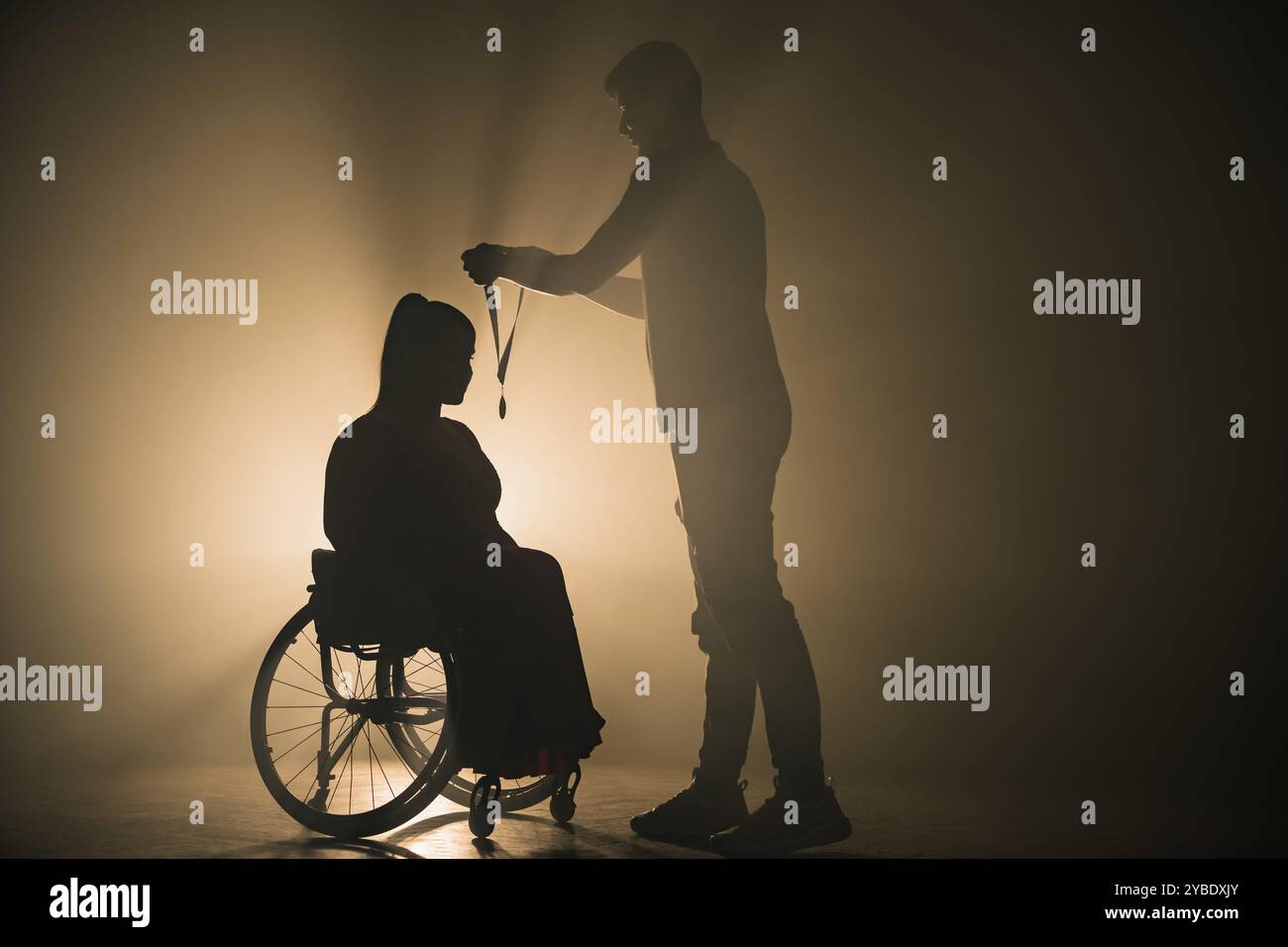 Woman in a wheelchair receiving a medal from a man on a dark stage ...