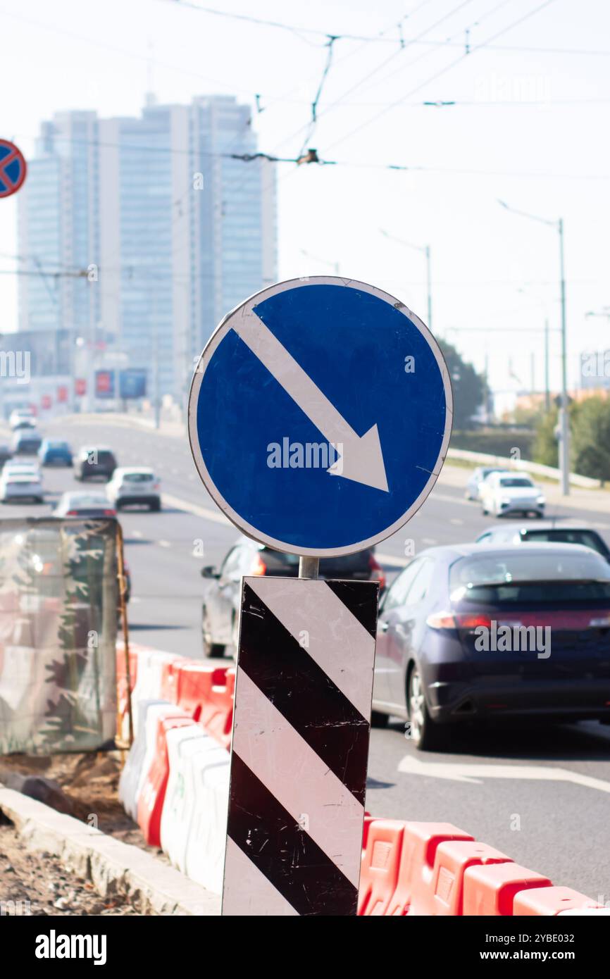 A blue sign featuring an arrow that is indicating a direction to the ...