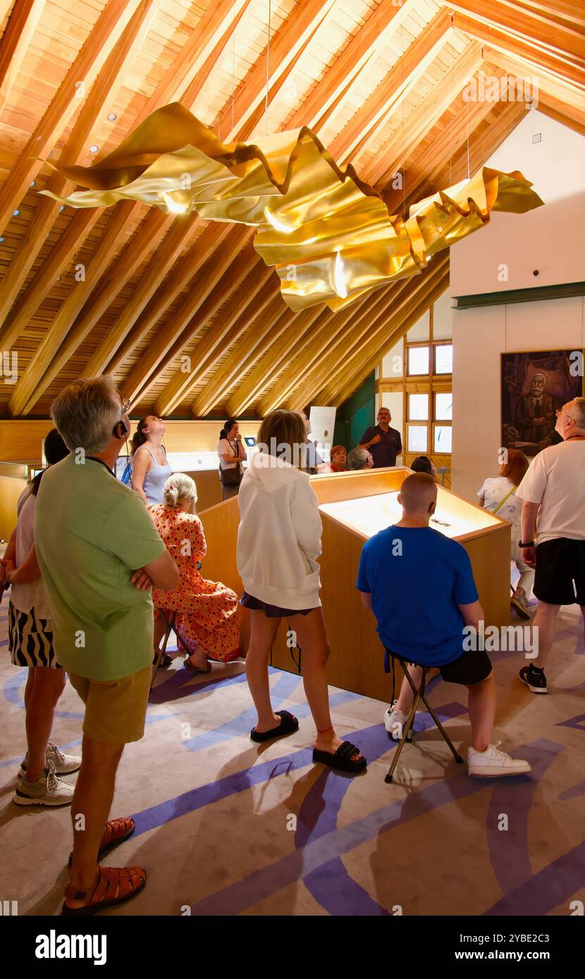 Tourists learning about the hanging metal sculpture Golden Ribbon or ...